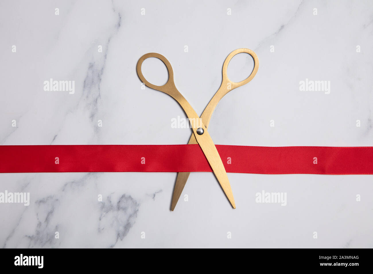 Grand opening background. Gold scissors with red ribbon on a marble ...