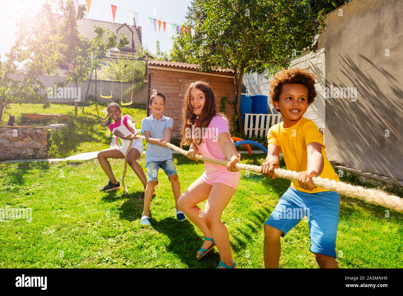 Group of kids play pulling rope game on the lawn Stock Photo - Alamy