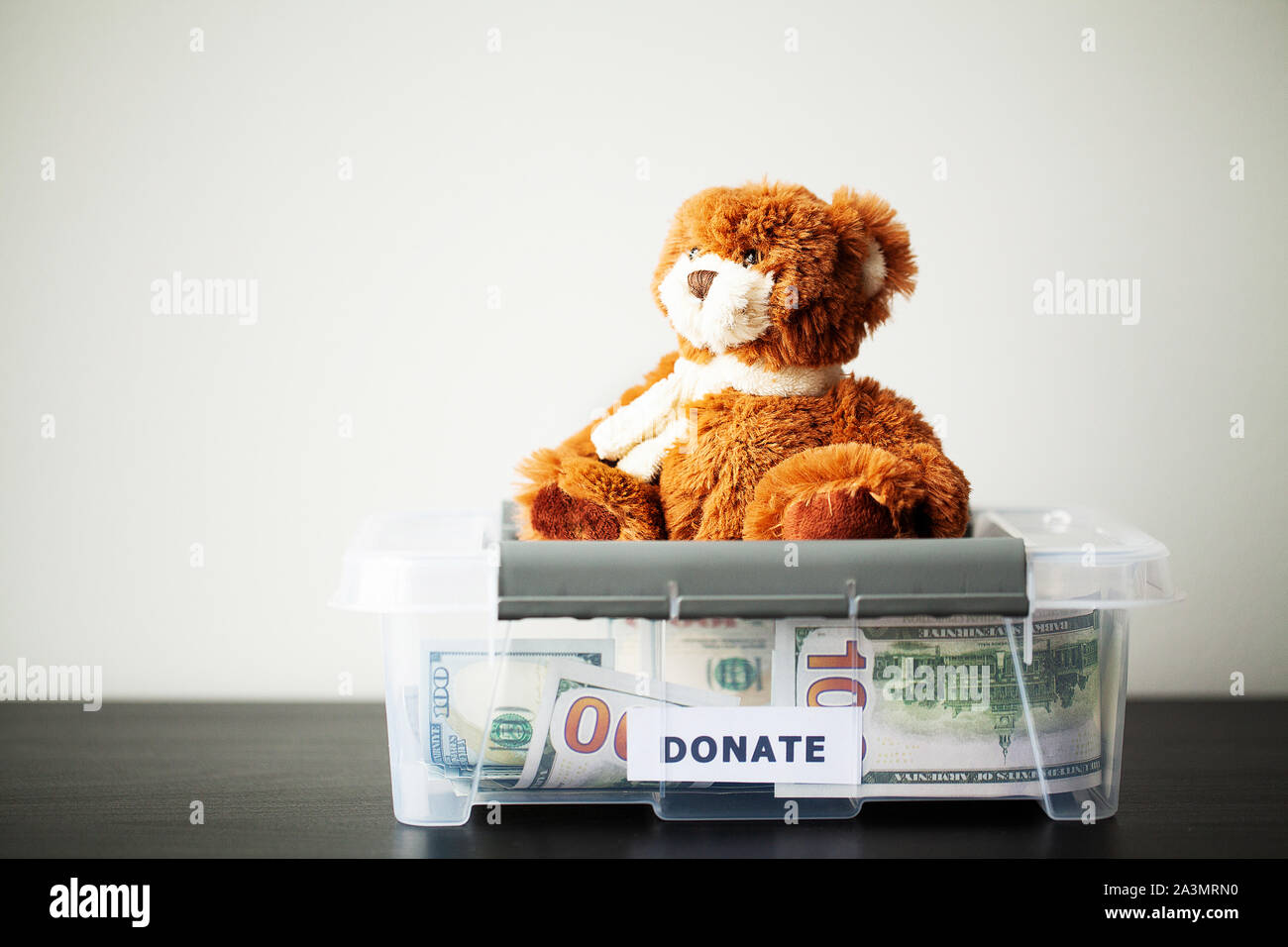 Donate box with dollars on wood desk Stock Photo - Alamy