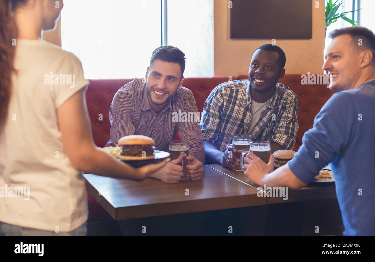 Hungry young guys looking at waitress serving food Stock Photo - Alamy