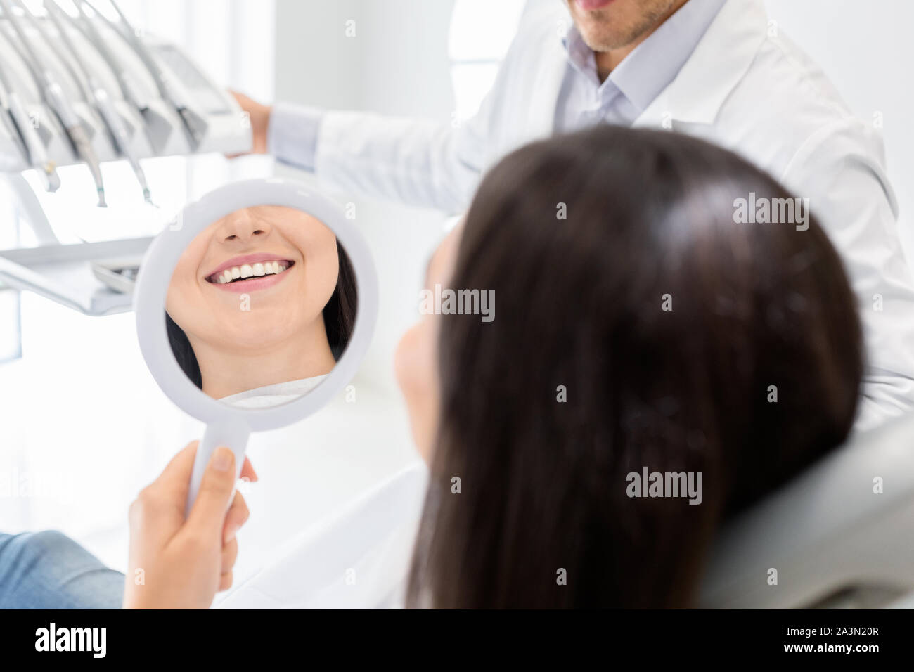 Happy female patient looking at mirror in dental clinic Stock Photo - Alamy