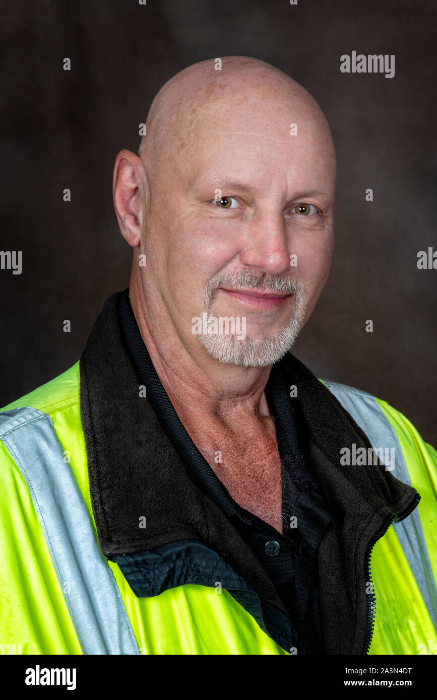 Vertical shot from the chest up of a friendly mature male worker in ...