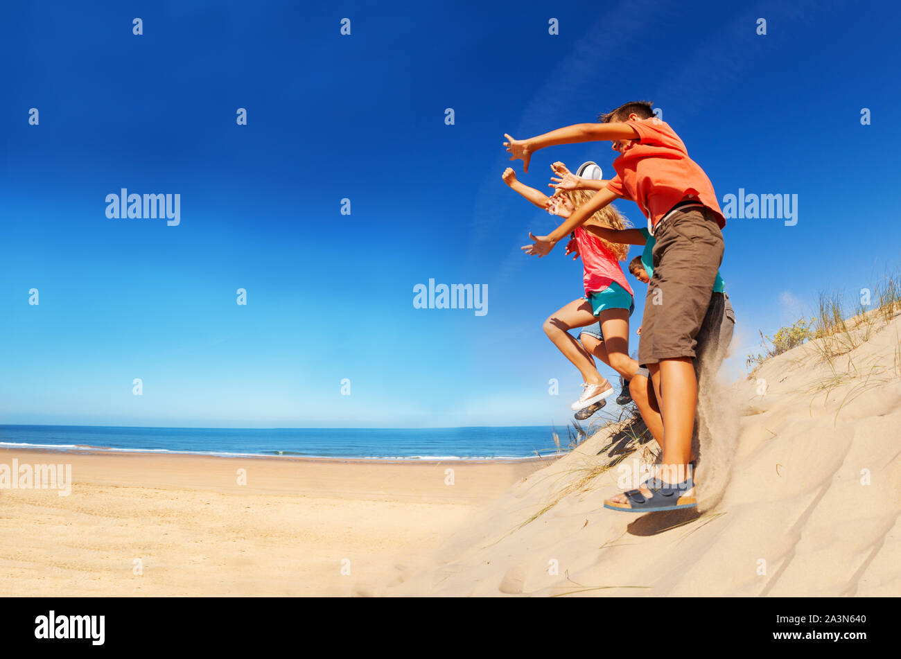 Many cute children jump from sand dune hands up Stock Photo - Alamy