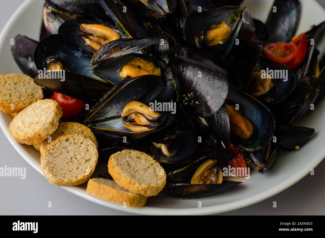 Close up of freshly cooked mussels with crisp bread and tomato. Healthy ...