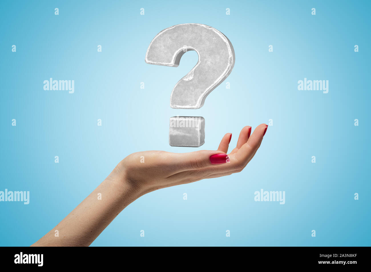 Stone question mark in air above woman's open palm on light-blue ...
