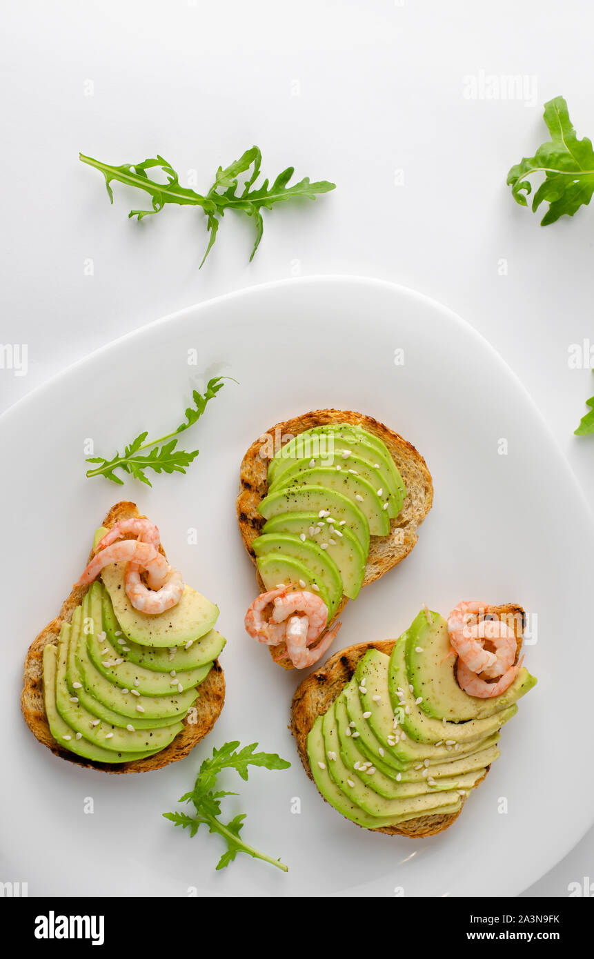 Healthy diet appetizer concept. Avocado toasts with arugula and shrimps ...