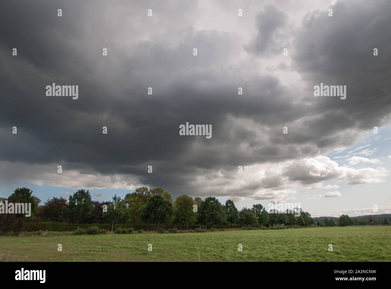 Dramatic dark rain clouds over a grove on the field edge Stock Photo ...