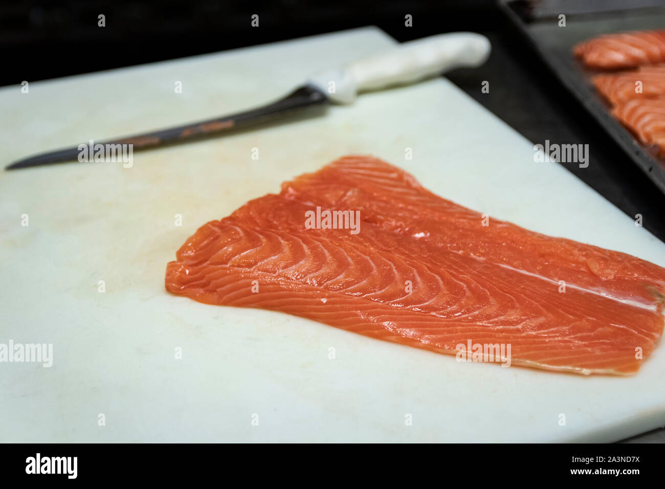 Raw filet of salmon on white cutting board with chef knife Stock Photo ...