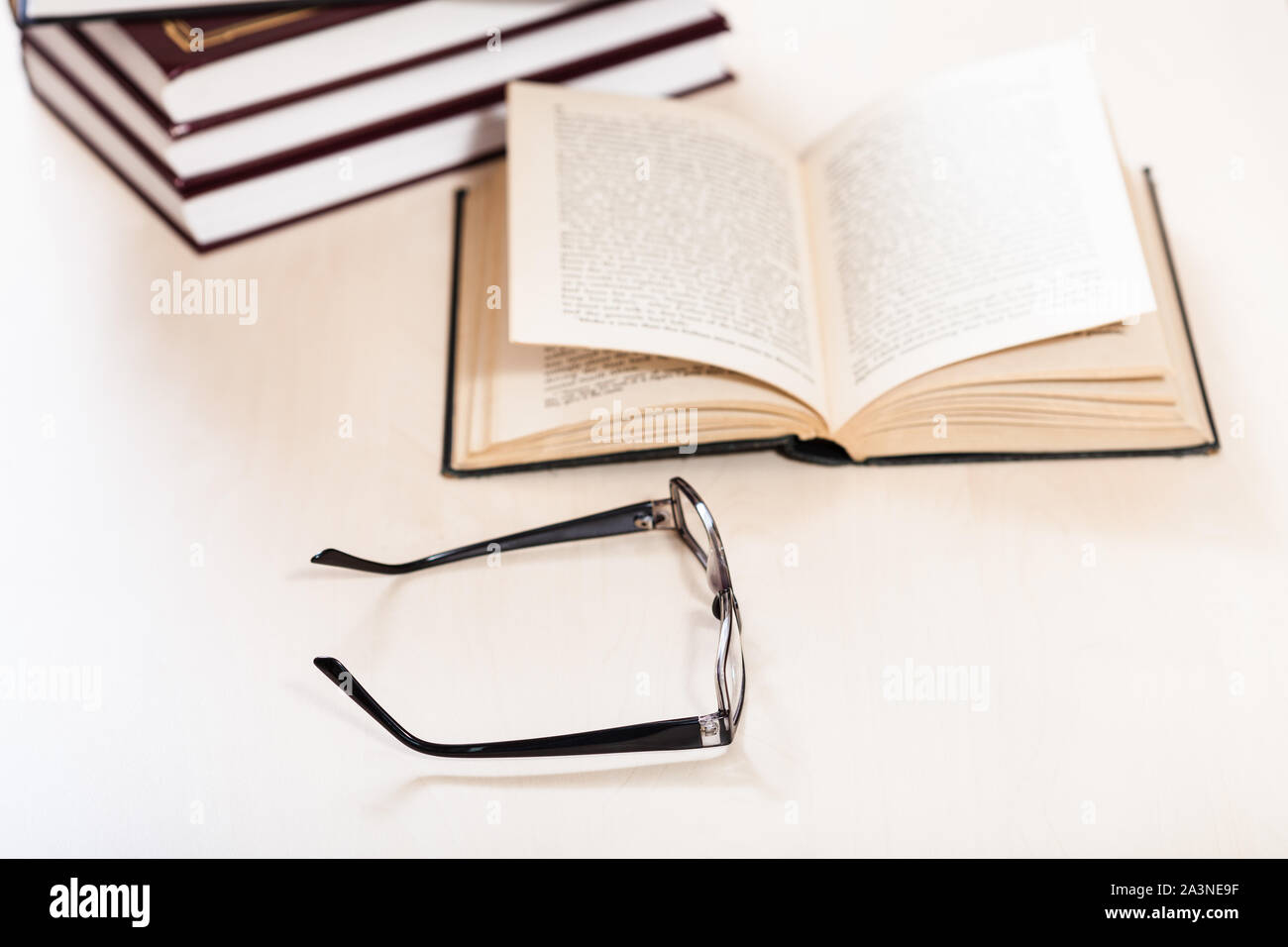 reading book with low vision - spectacles and open book near stack of ...