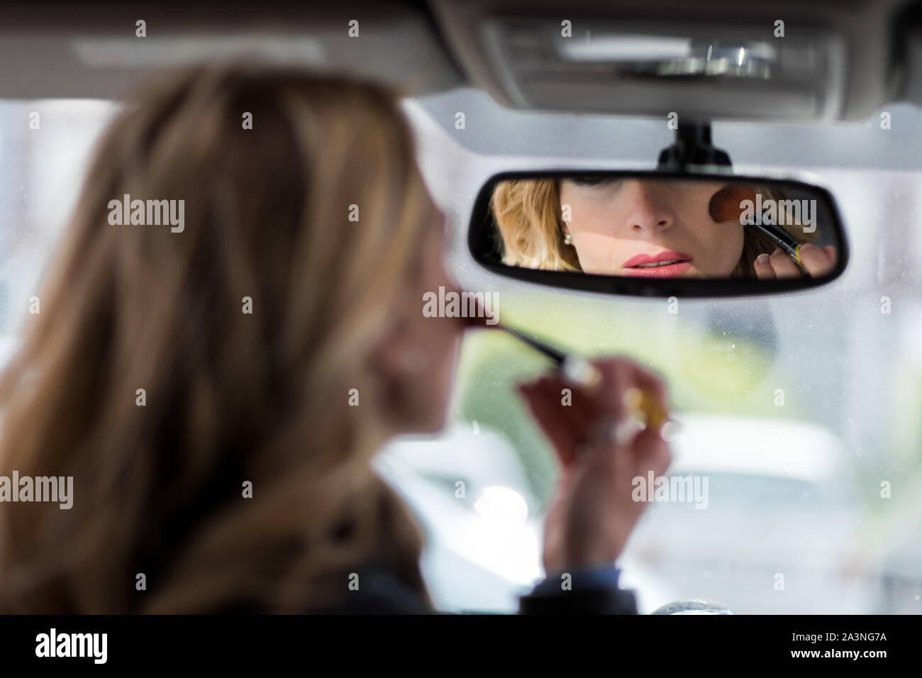 Beautiful young woman applying make-up while driving car Stock Photo ...