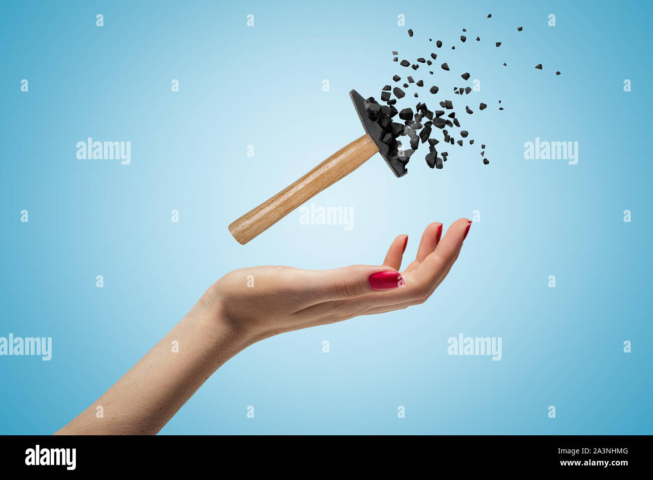 Female hand holding small hammer shattering into pieces on blue ...