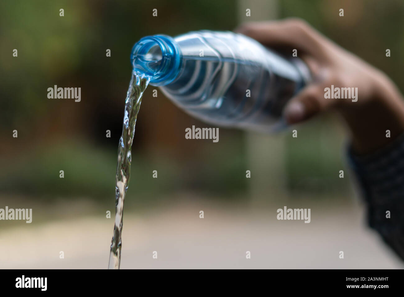 hand holding plastic bottle and pouring water from it Stock Photo - Alamy