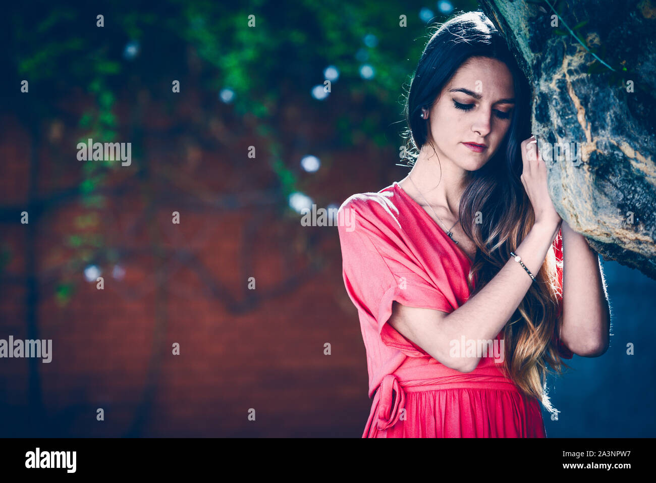 Young sad woman standing alone, leaning on a tree at park Stock Photo ...