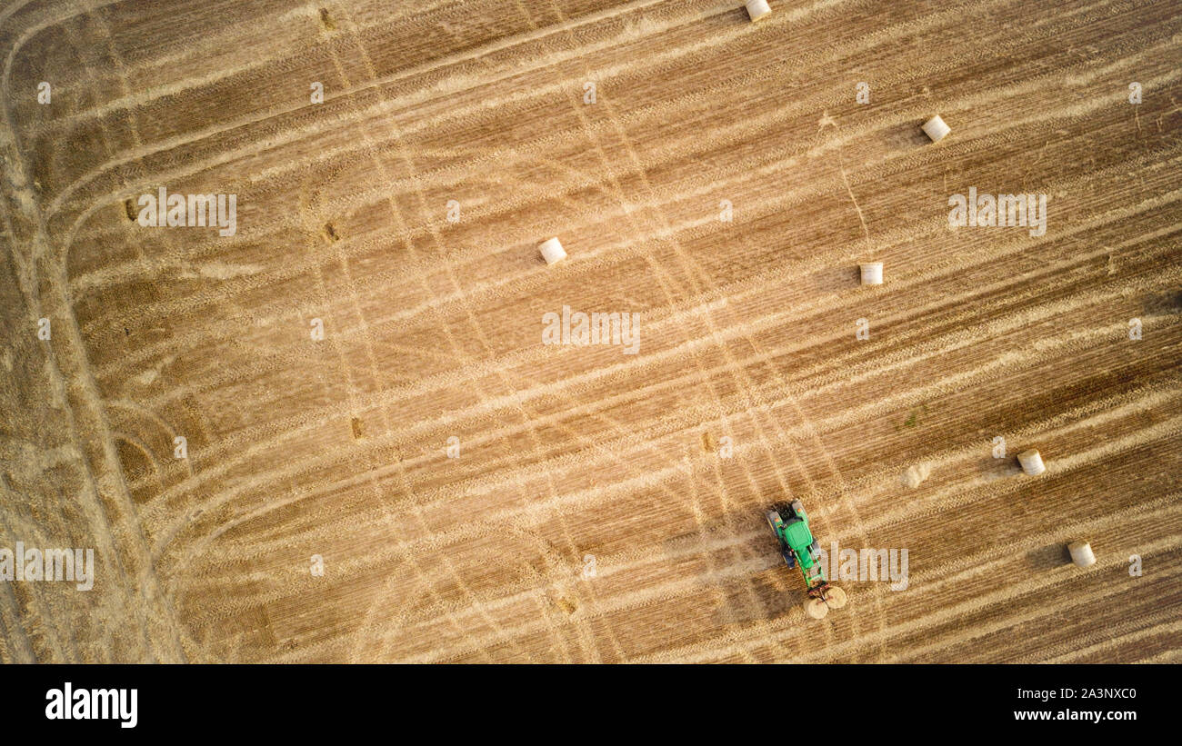 aerial drone view of tractor and trailer baling bales in a ...
