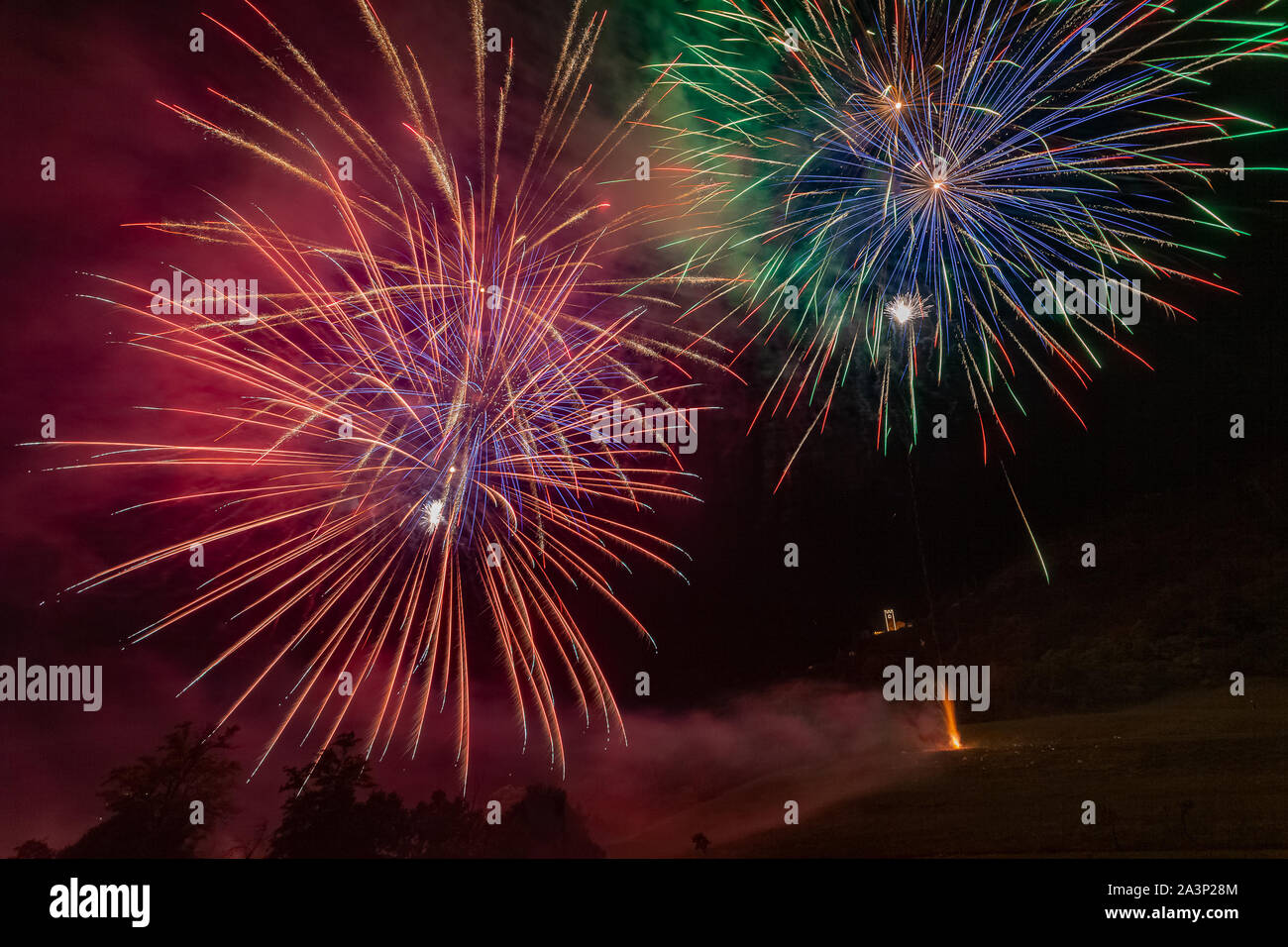 Awesome multi color fireworks explosions lighting sky over trees ...