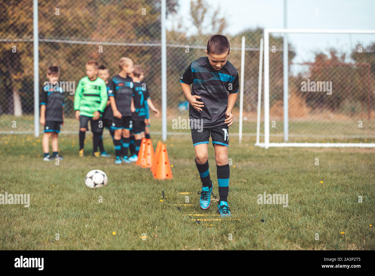 Kids soccer players Jogging and jump between marker for football ...