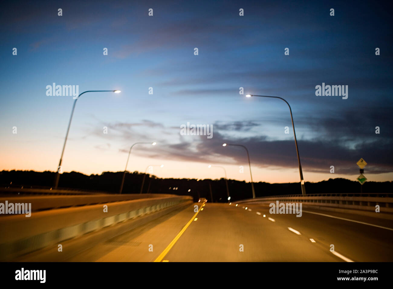 Illuminated street lights over a highway at dusk Stock Photo - Alamy