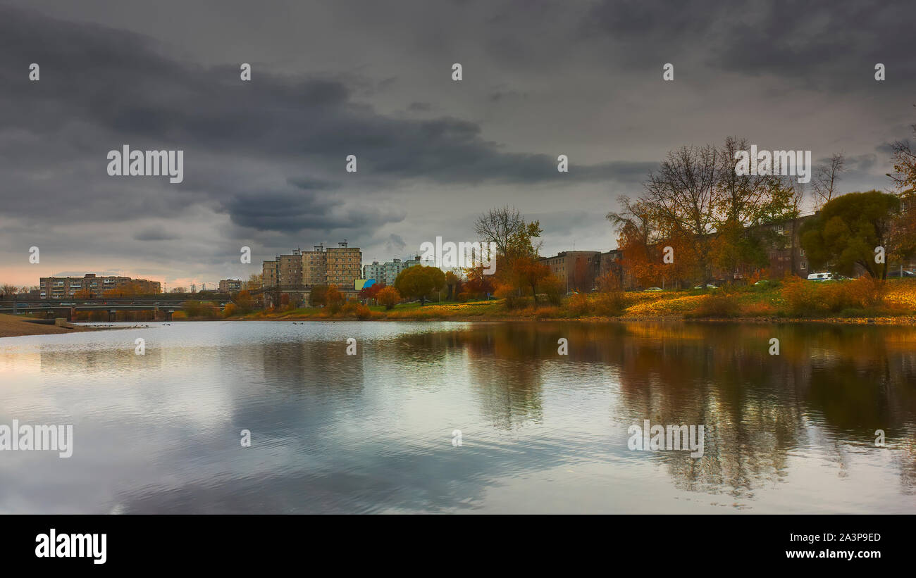 Autumn city landscape trees with colorful foliage are reflected in the ...