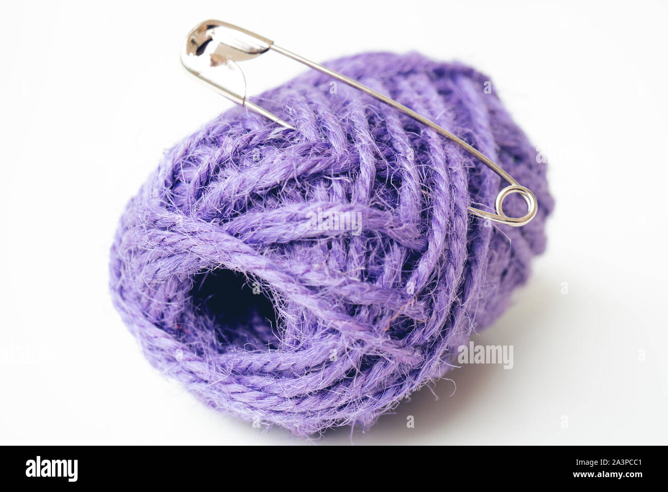 Picture of safety pin and purple yarn. Isolated on the white background ...