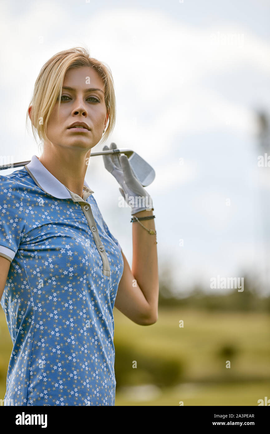 Portrait of a beautiful woman playing golf on a green field outdoors ...