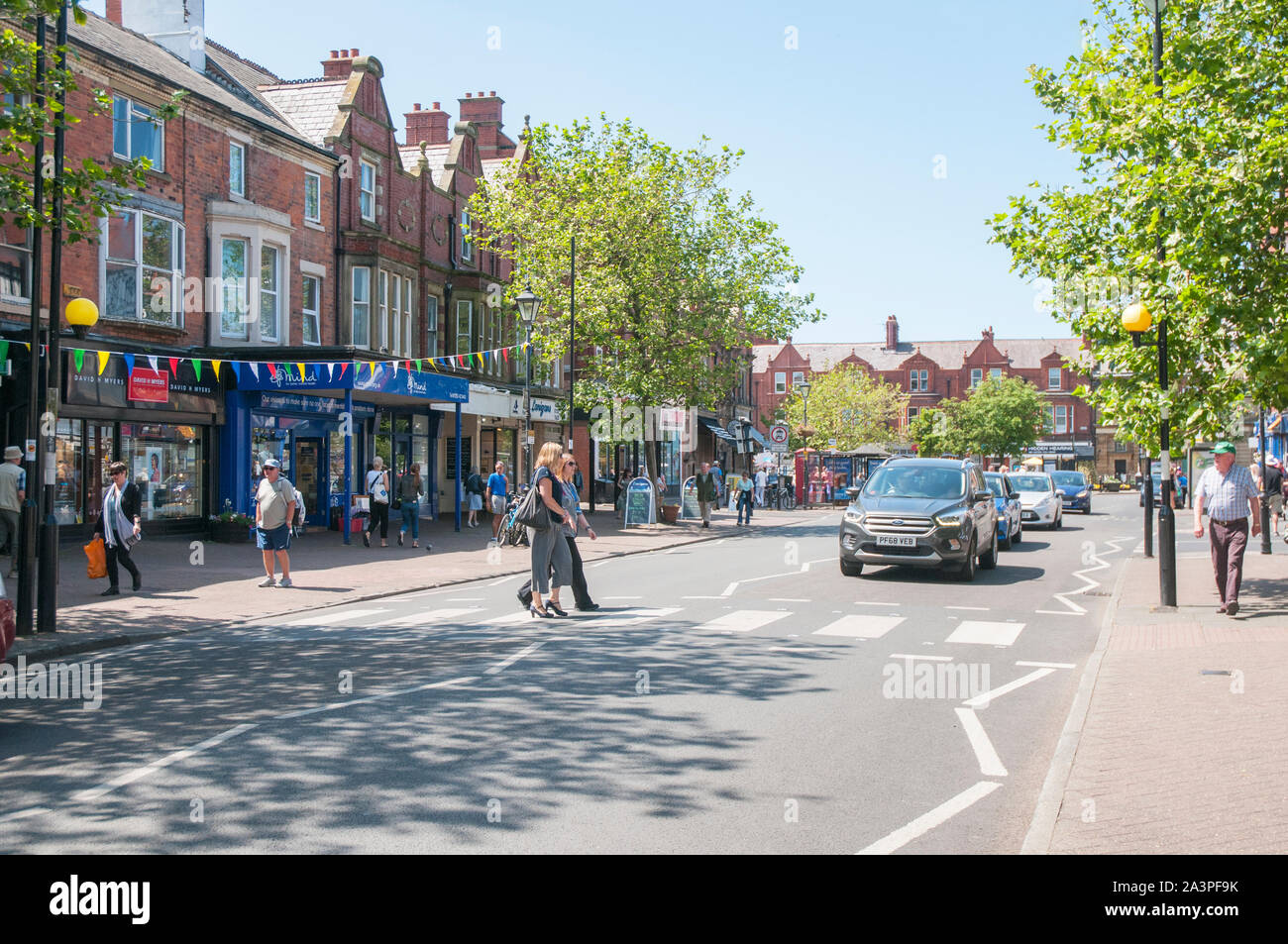 Cars waiting whilst two young ladies walk across the road on a Zebra ...