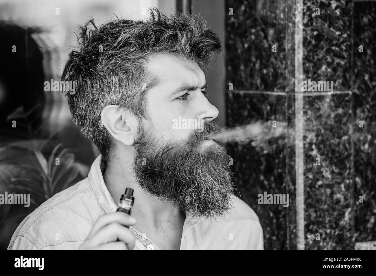 Bearded brutal male smoking electronic cigarette. Mature hipster with ...