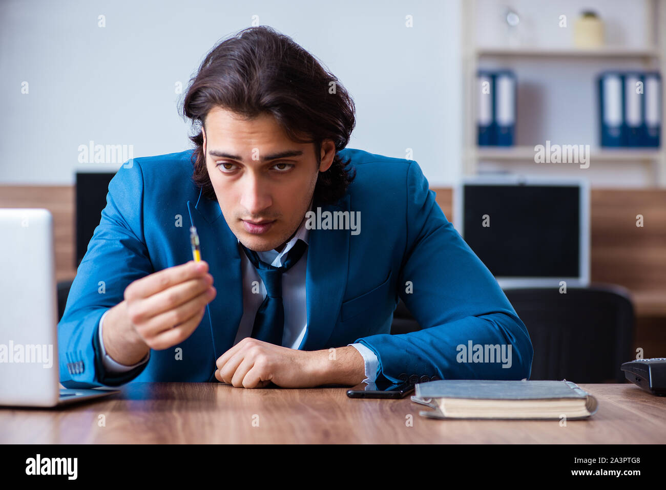 The young man having problems with narcotics at workplace Stock Photo ...