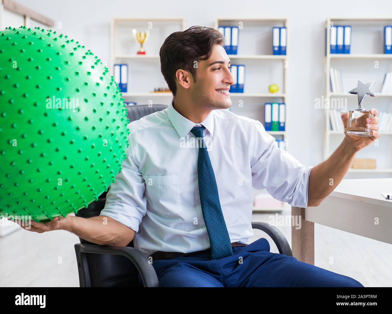 The young businessman doing sports stretching at workplace Stock Photo ...