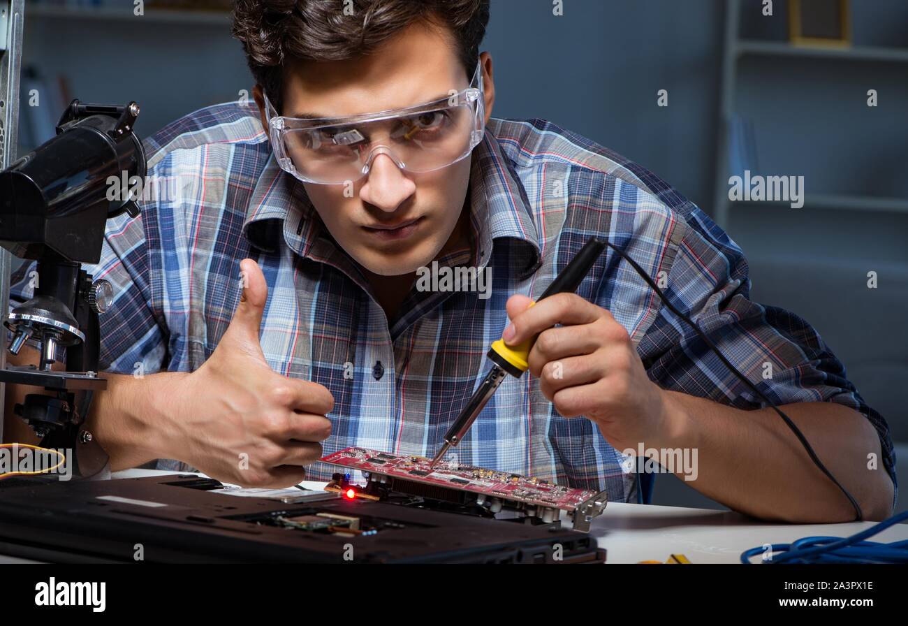 Young repair technician soldering electrical parts on motherboard Stock ...