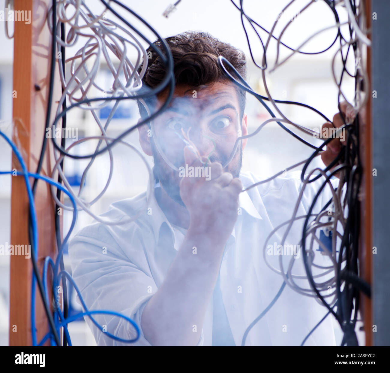 The electrician trying to untangle wires in repair concept Stock Photo ...