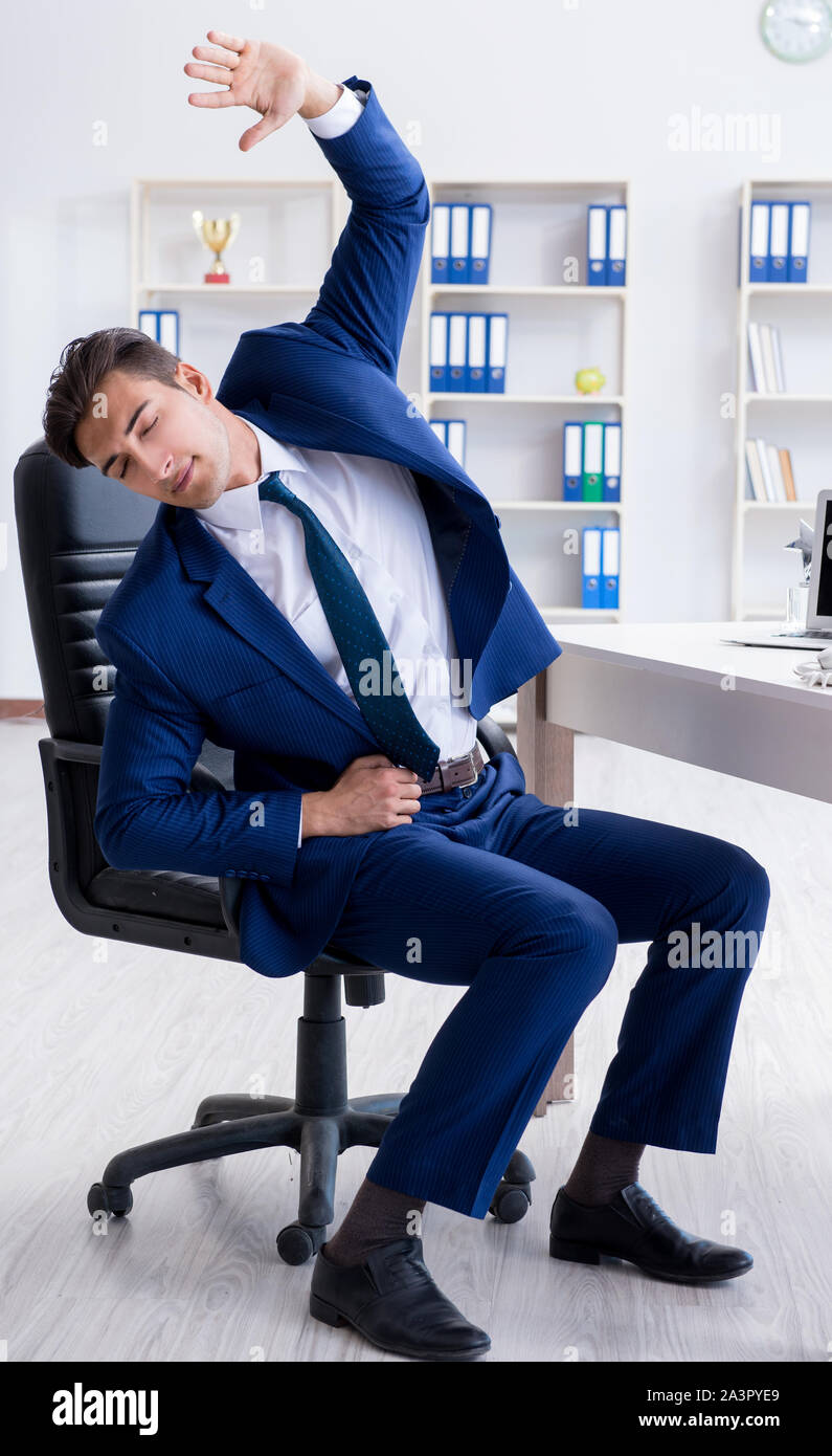 The young businessman doing sports stretching at workplace Stock Photo ...
