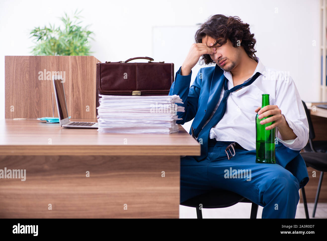 The young drunk employee in the office Stock Photo - Alamy