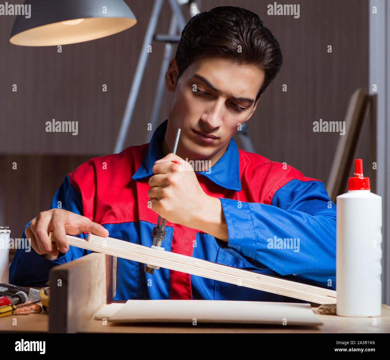Young man gluing wood pieces together in DIY concept Stock Photo - Alamy