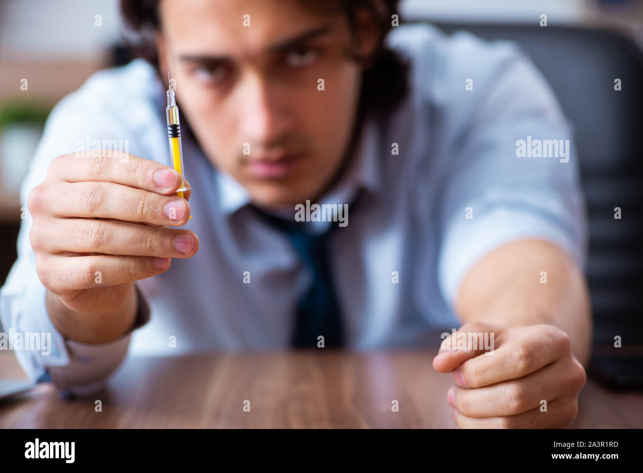 The young man having problems with narcotics at workplace Stock Photo ...