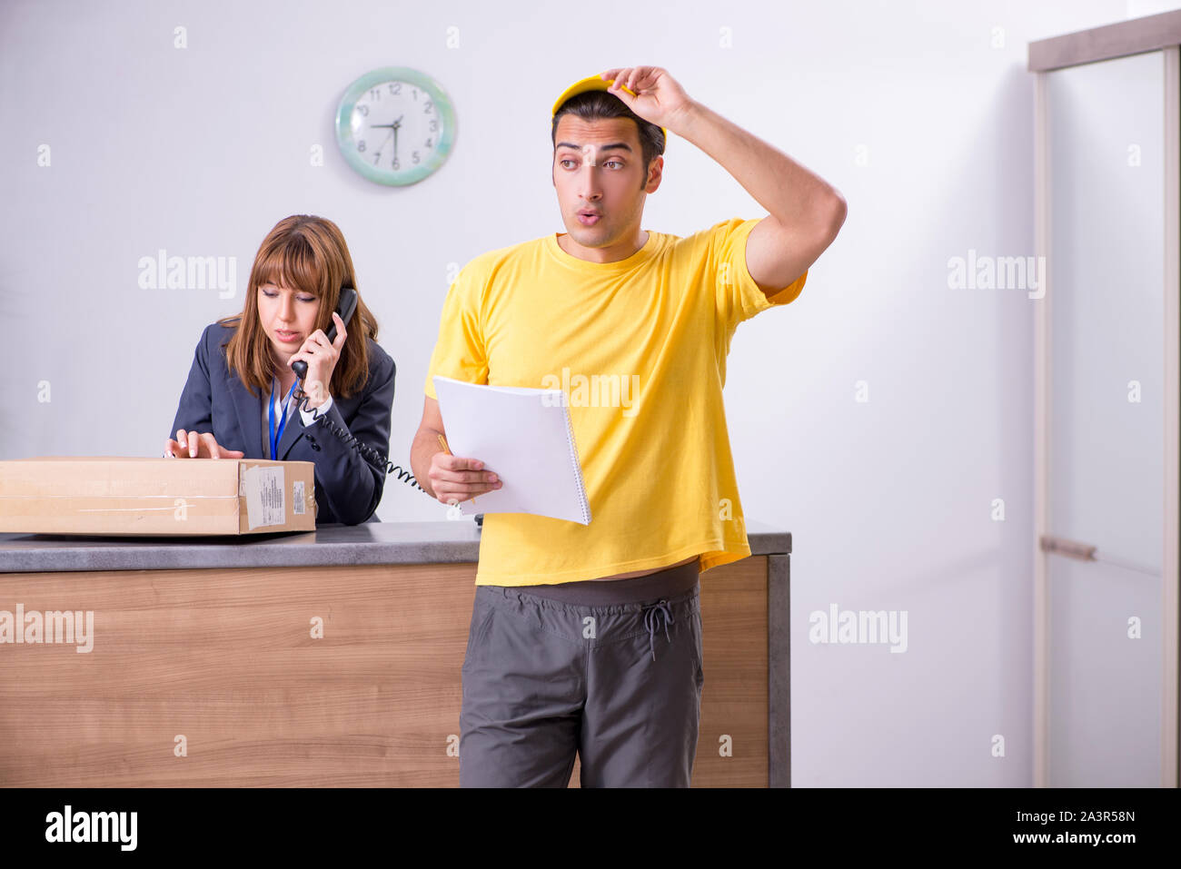 The young male courier delivering box to hotel's reception Stock Photo ...