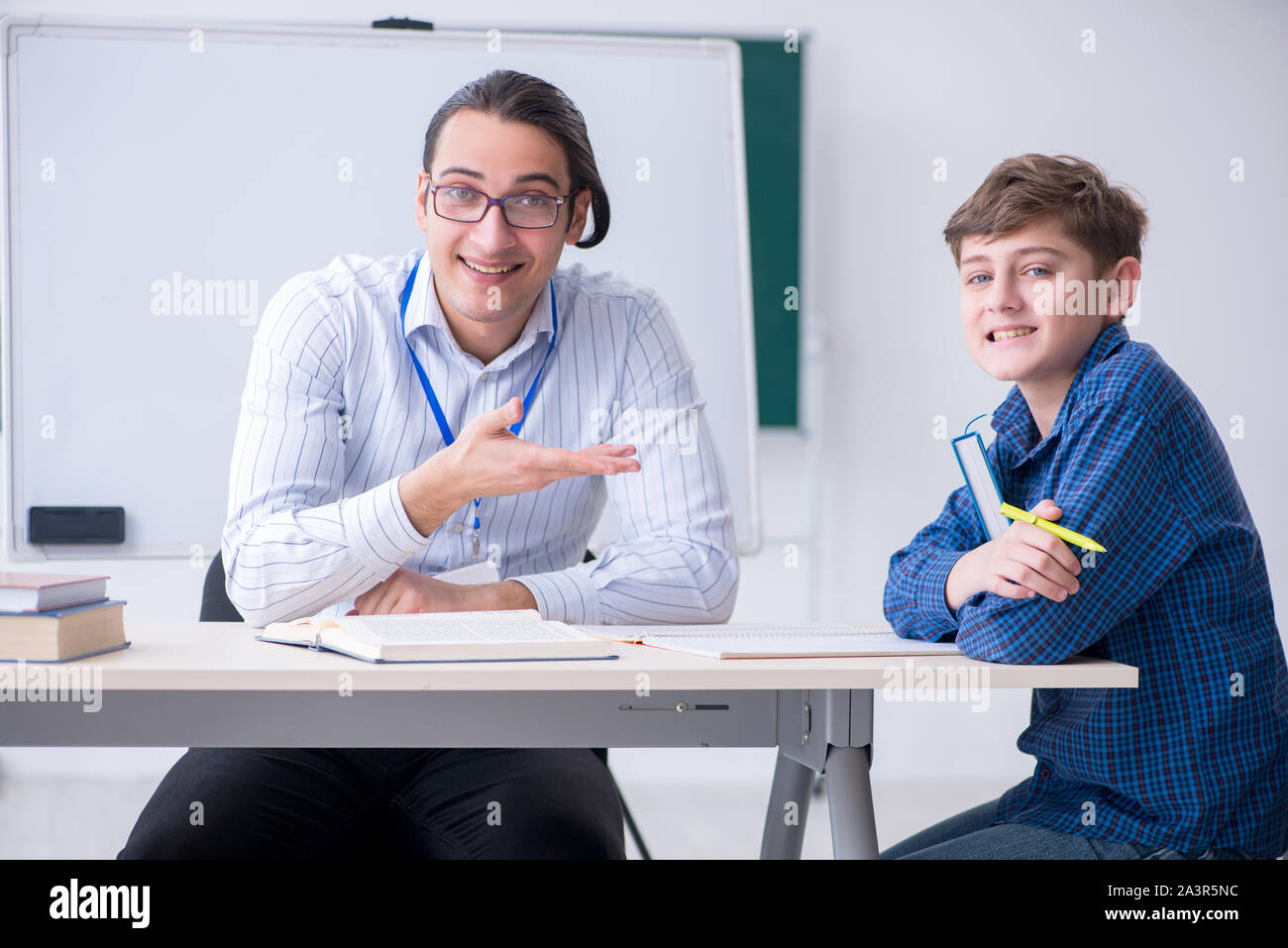 The young male teacher and boy in the classroom Stock Photo - Alamy