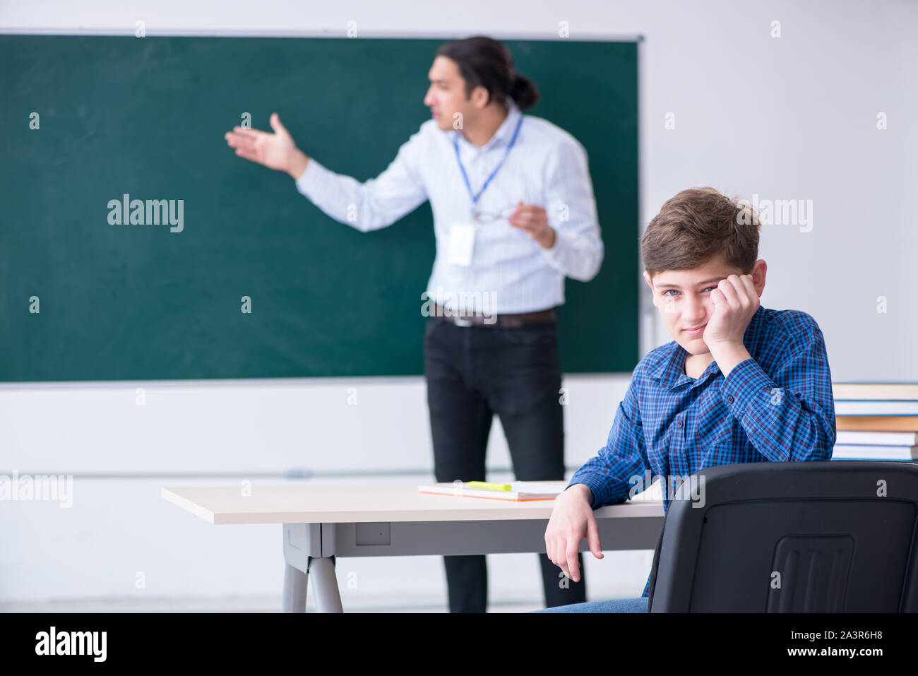 The young male teacher and boy in the classroom Stock Photo - Alamy