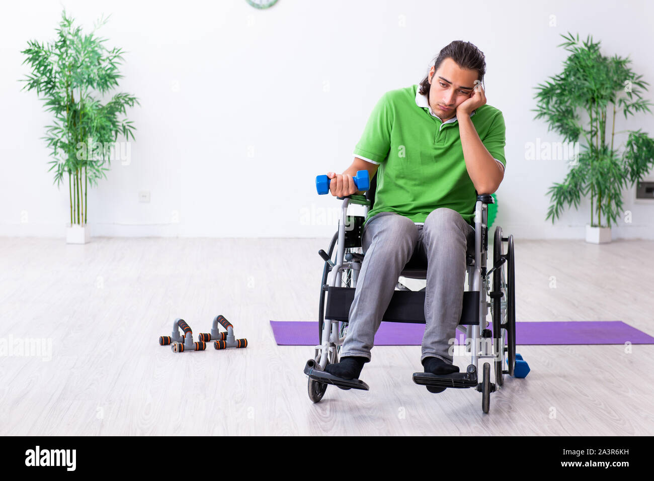 The young man in wheel-chair doing exercises indoors Stock Photo - Alamy