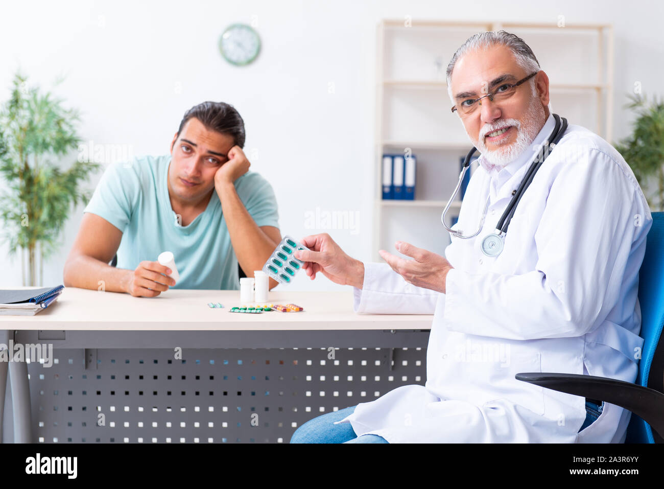 The young man visiting old male doctor Stock Photo - Alamy