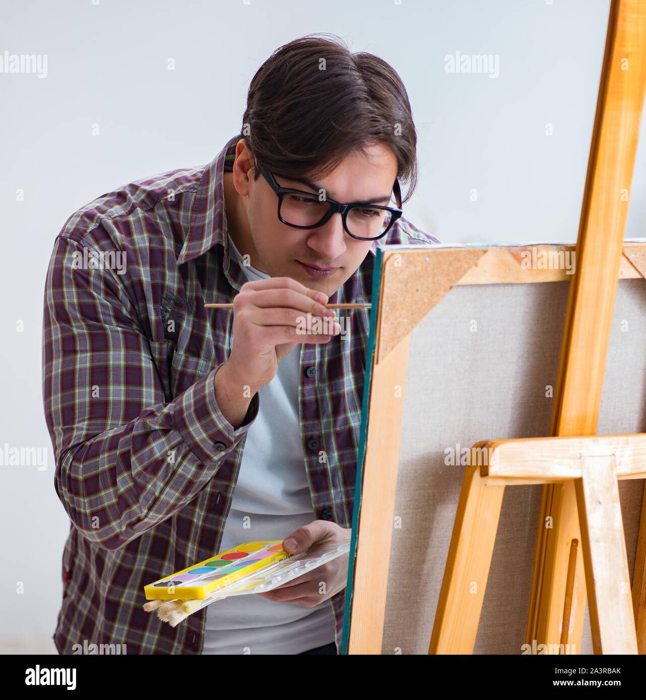 The young male artist drawing pictures in bright studio Stock Photo - Alamy
