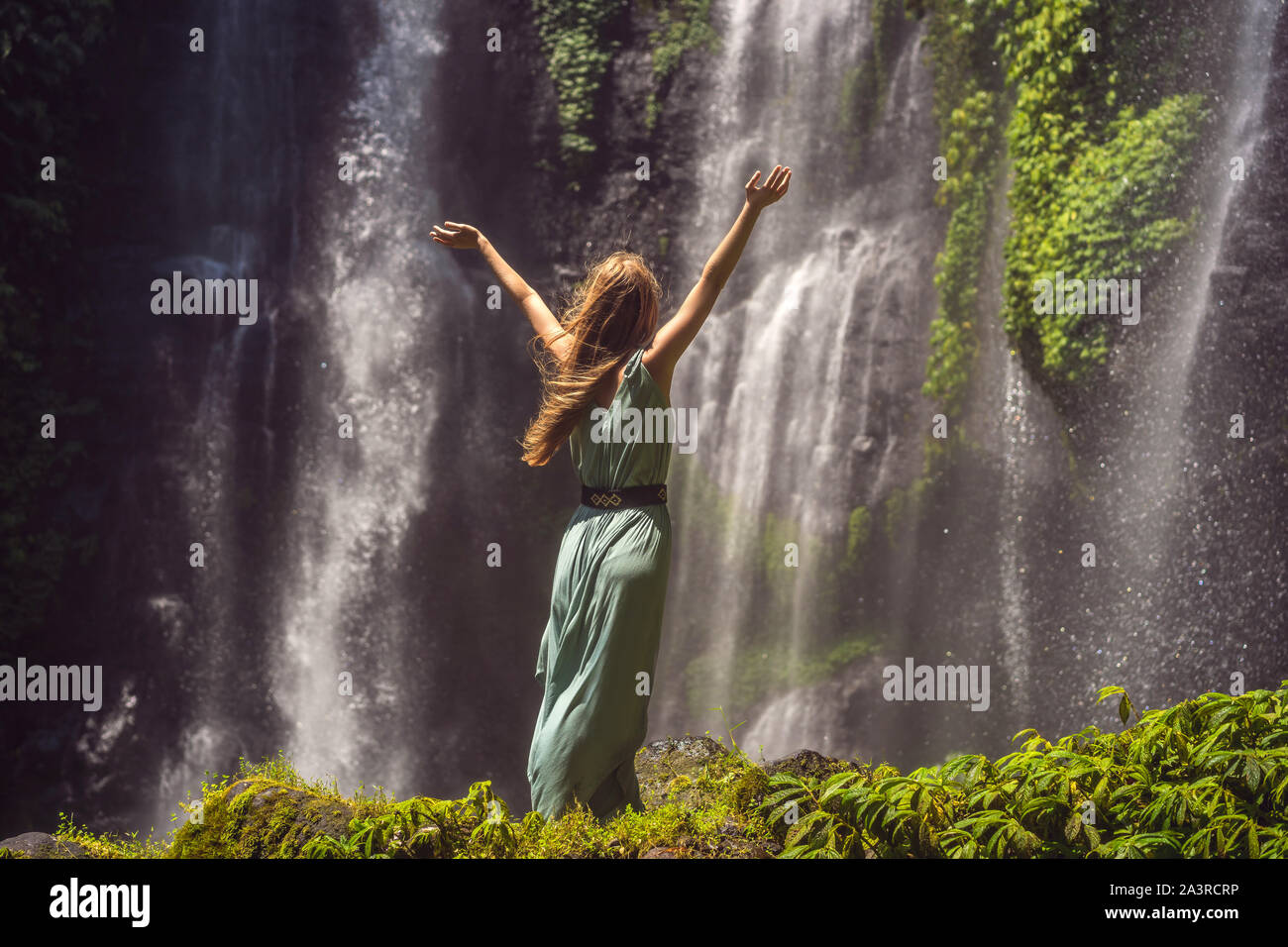Woman in turquoise dress at the Sekumpul waterfalls in jungles on Bali ...