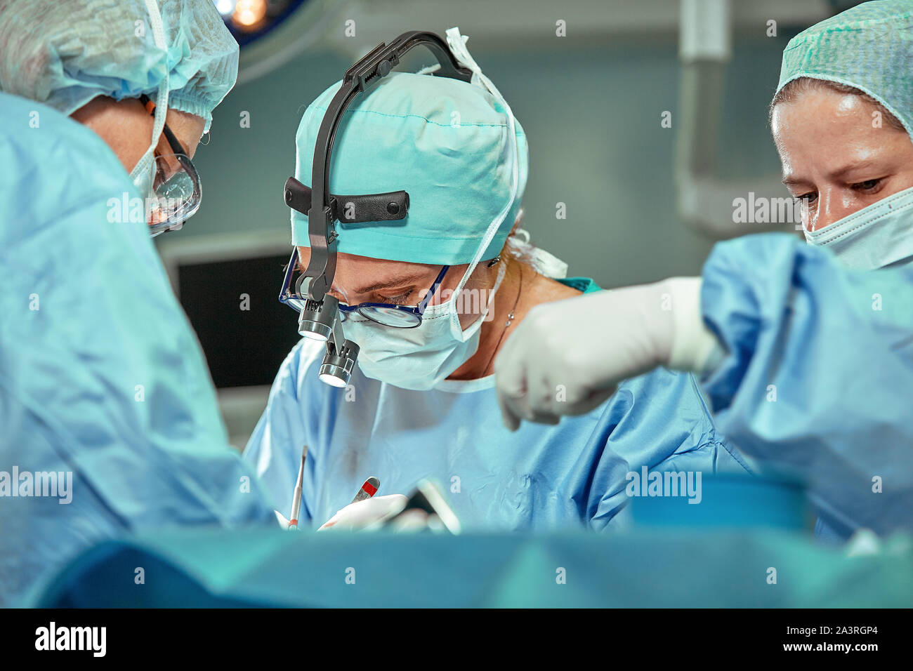 Group of surgeons looking at patient on operation table during their ...