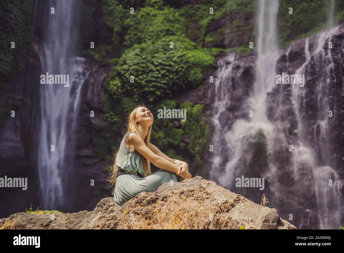 Woman in turquoise dress at the Sekumpul waterfalls in jungles on Bali ...
