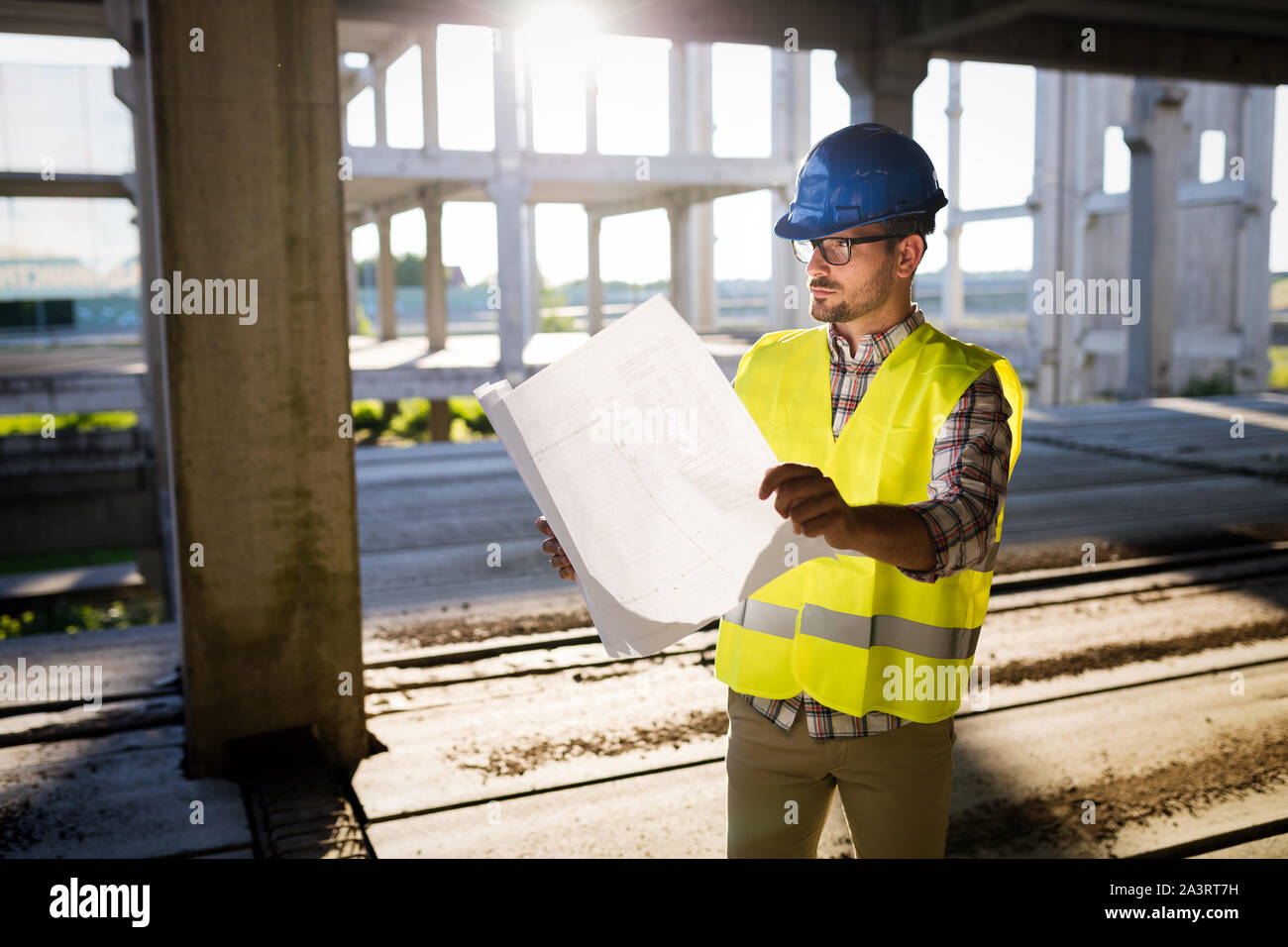 Engineer working on construction site and holding blueprint Stock Photo ...