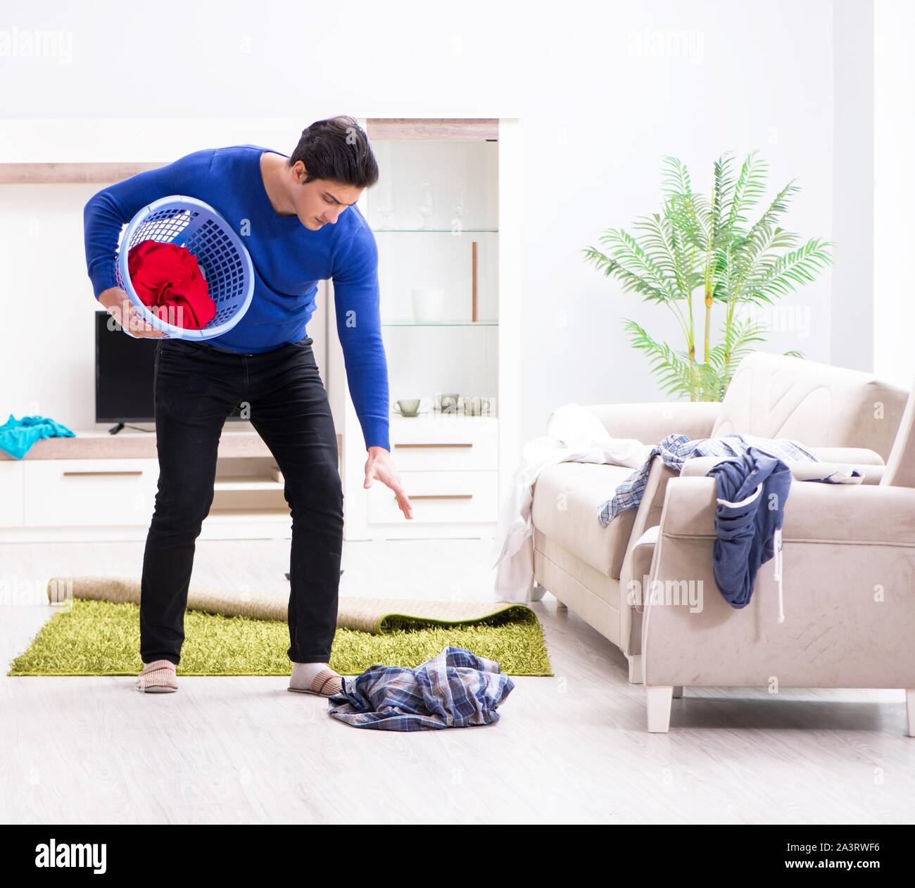 The young man collecting dirty clothing for laundry Stock Photo - Alamy