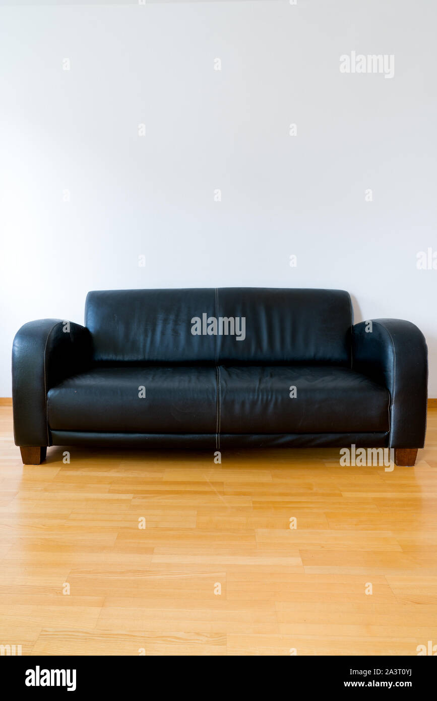 A vertical view of a dark brown leather couch in a minimalist apartment ...