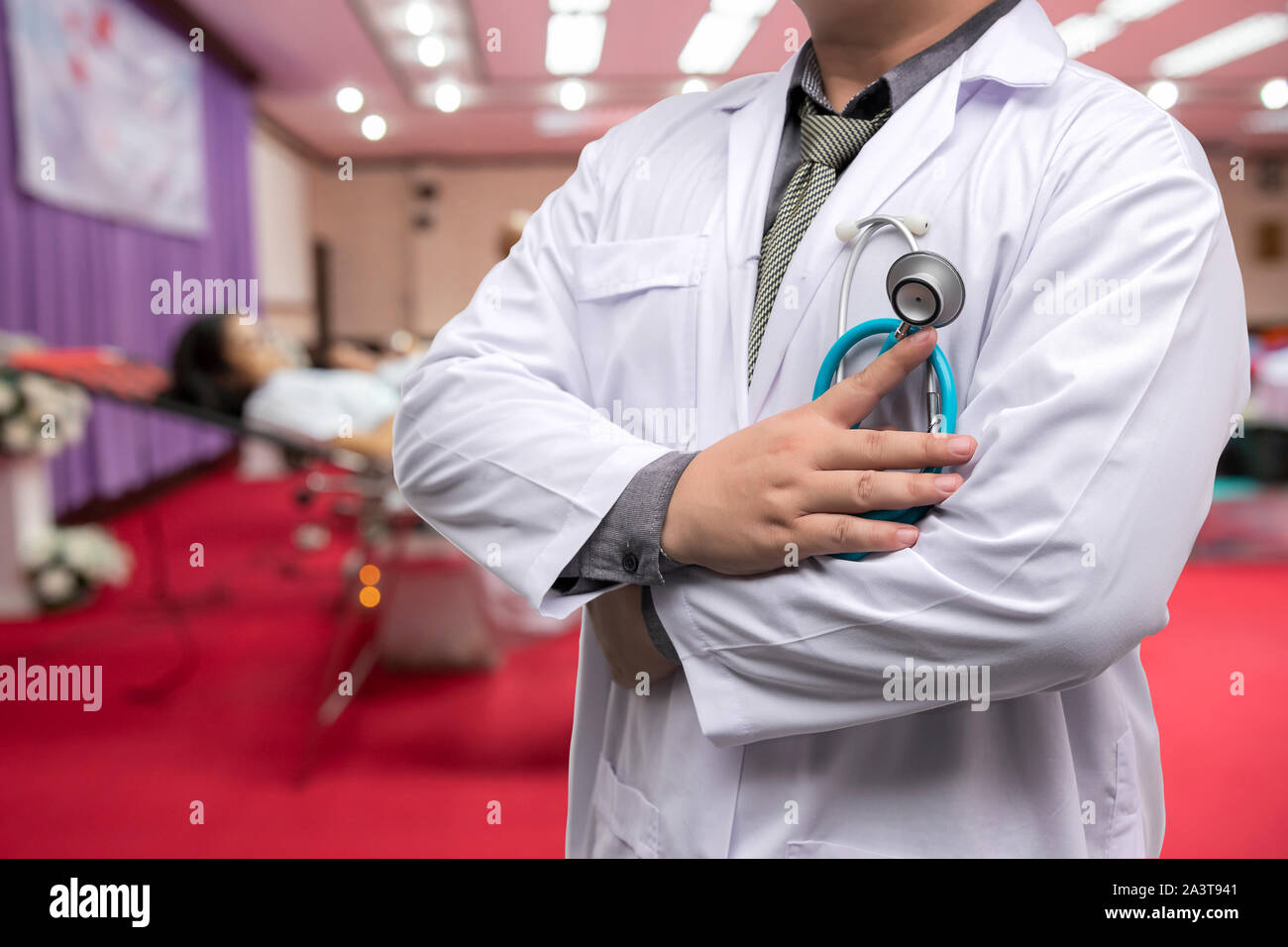 Doctor in gown uniform with stethoscope standing and fold his arms over ...