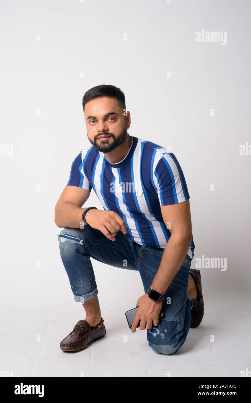 Full body shot of young bearded Indian man crouching Stock Photo - Alamy