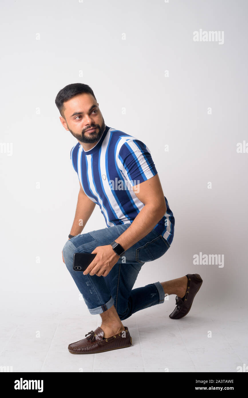 Full body shot of young bearded Indian man crouching Stock Photo - Alamy