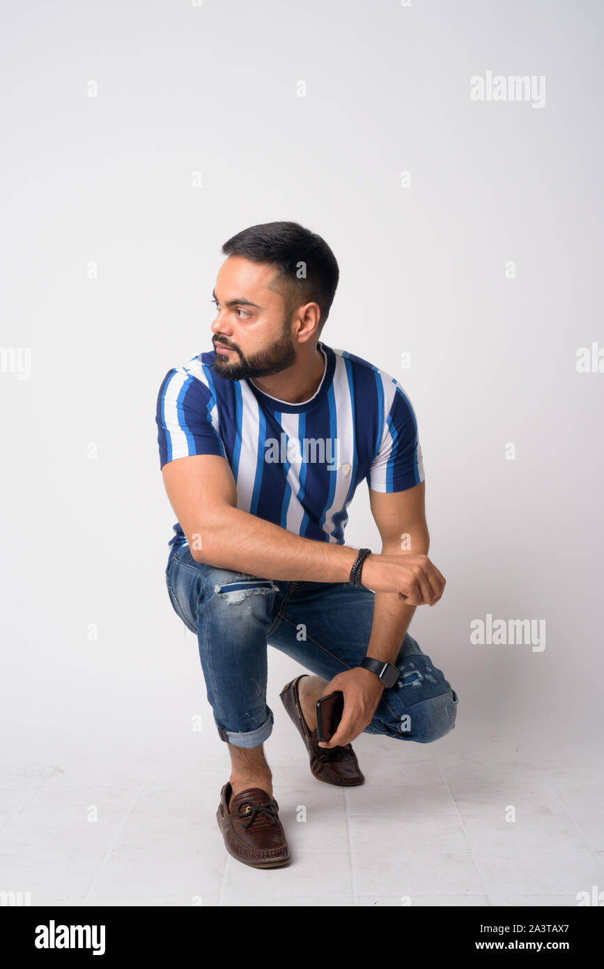 Full body shot of young bearded Indian man crouching Stock Photo - Alamy